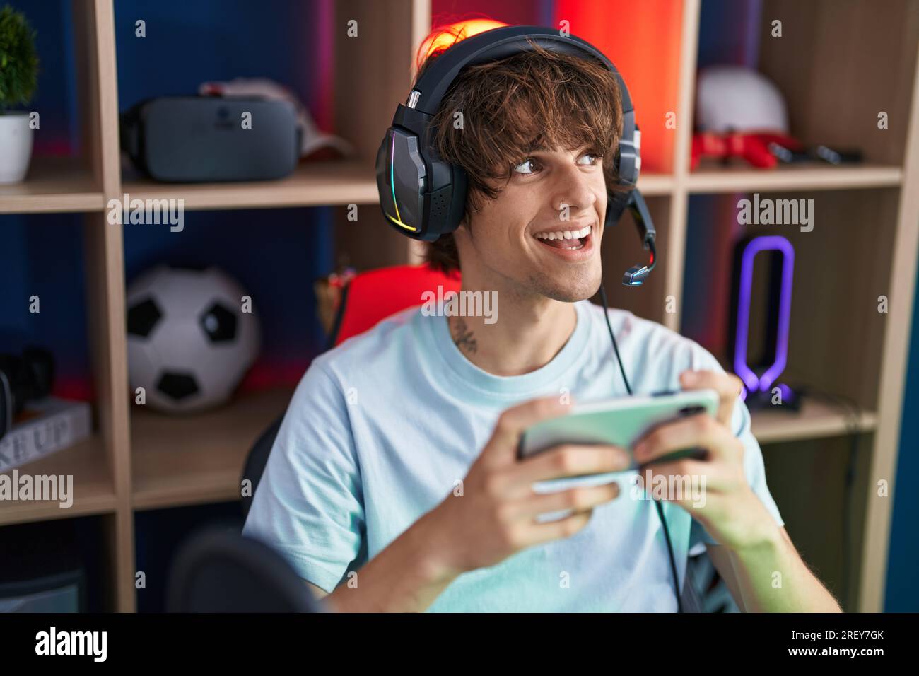 Young blond man streamer playing video game using smartphone at gaming ...
