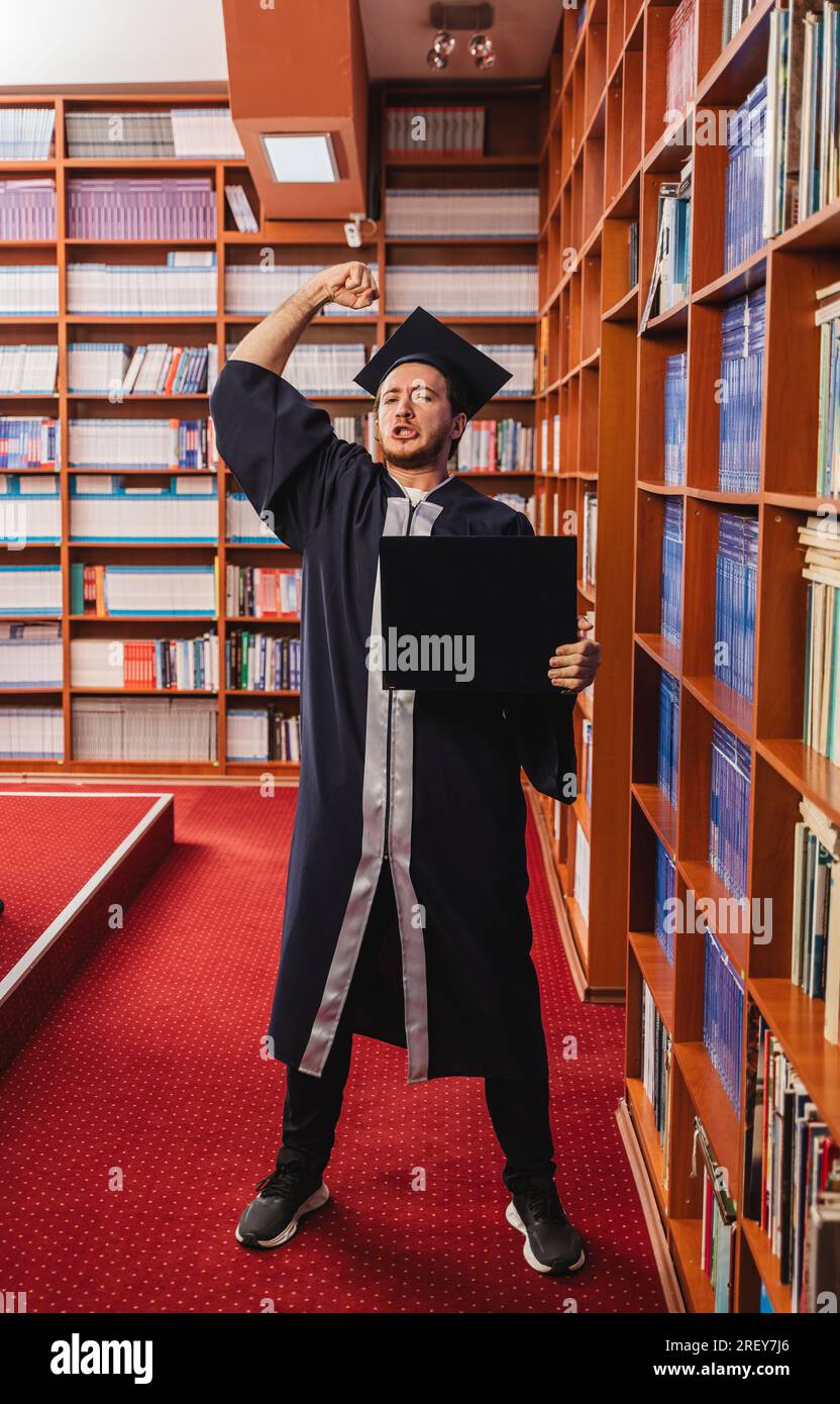 Excited and young male proudly holding his university degree in a ...