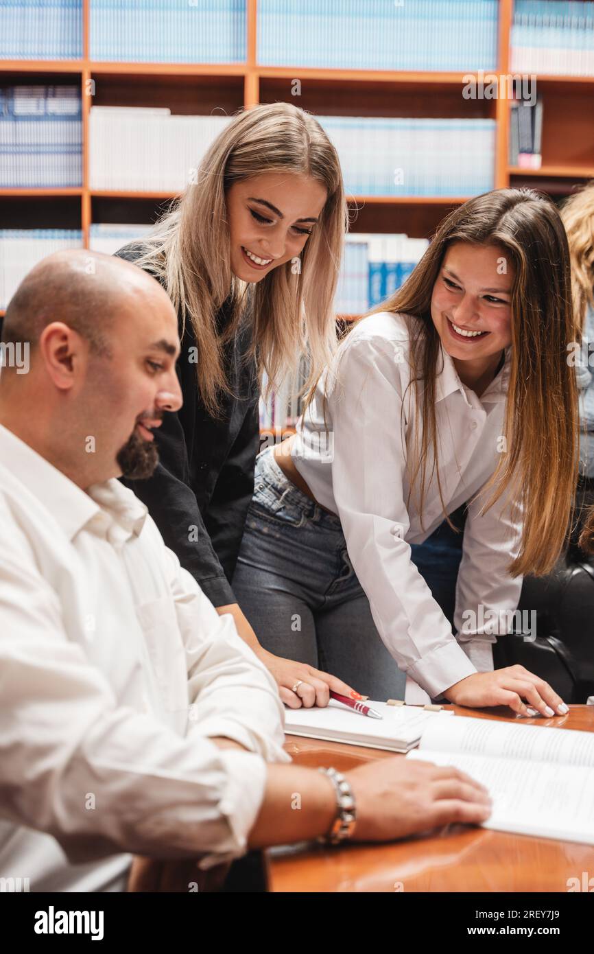 Two young and beautiful female students listening and smiling to their ...