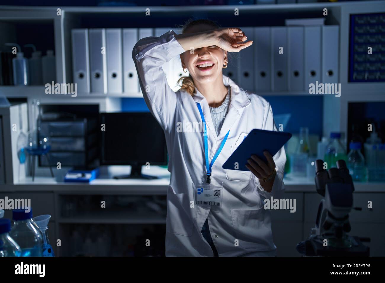 Beautiful blonde woman working at scientist laboratory late at night ...
