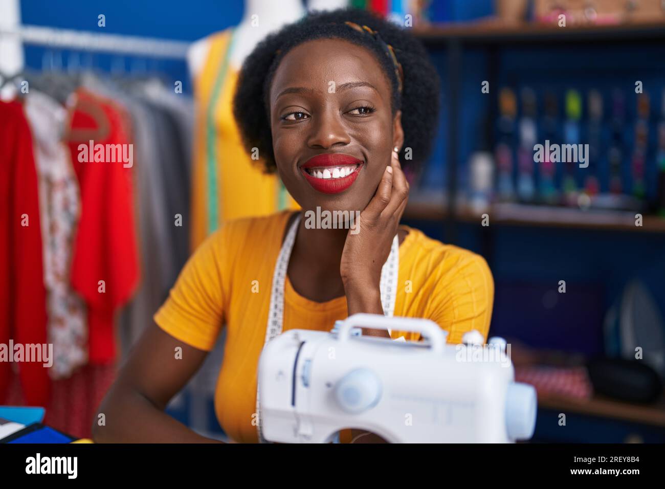 African american woman tailor smiling confident using sewing machine at ...