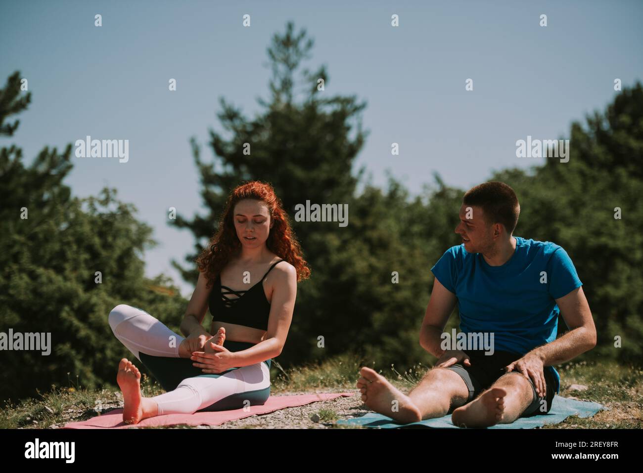Yoga couple talking and making yoga poses at the top of the mountain ...