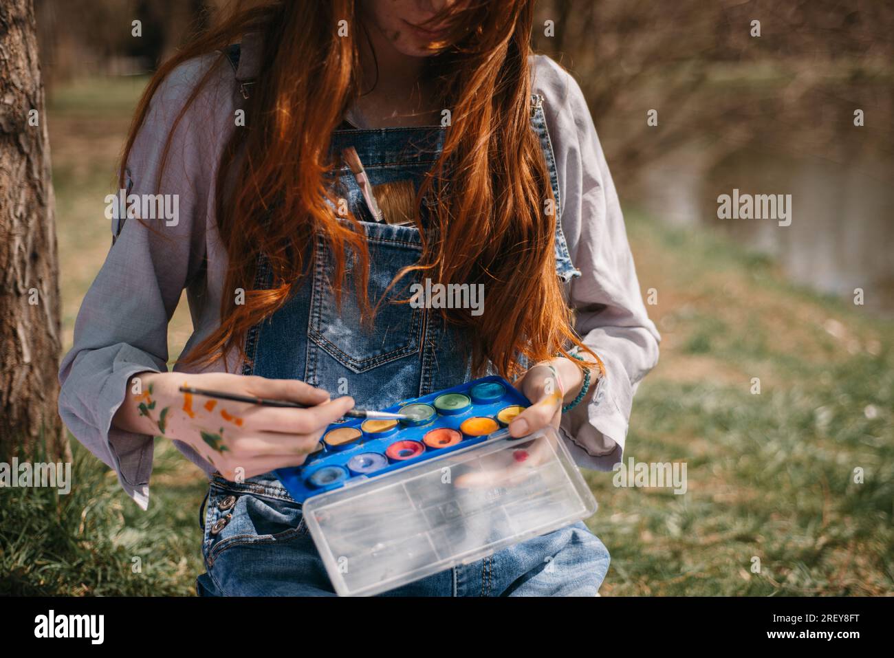 Close up of ginger girl painter sitting at the park with her color ...