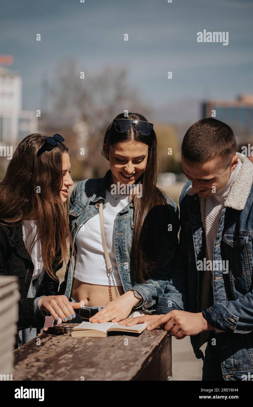Close up of three best friends reading a book together while standing ...
