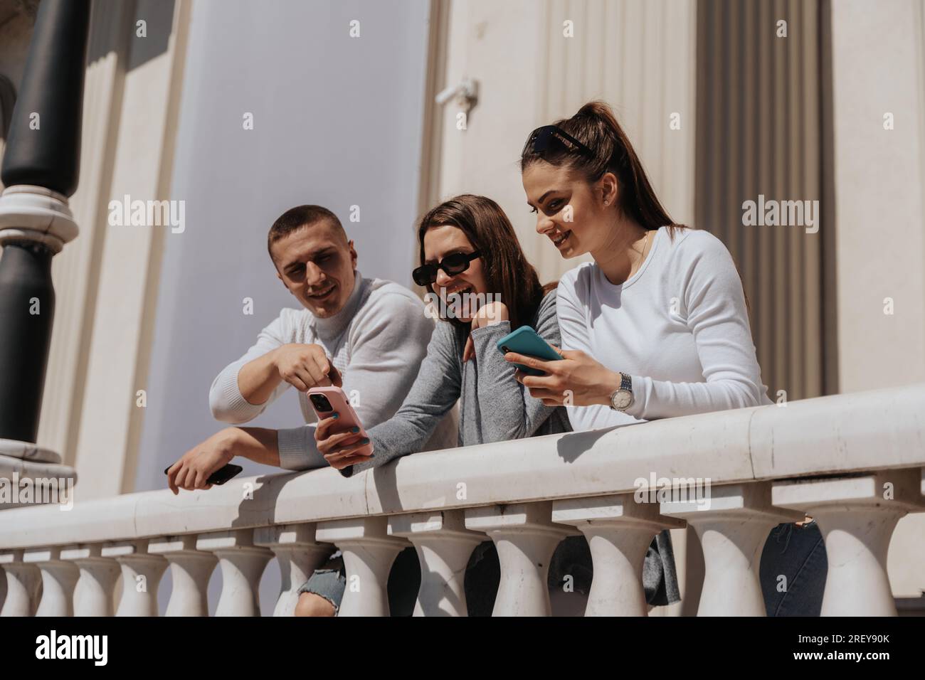 Handsome man pointing at his friends phone and laughing together while ...