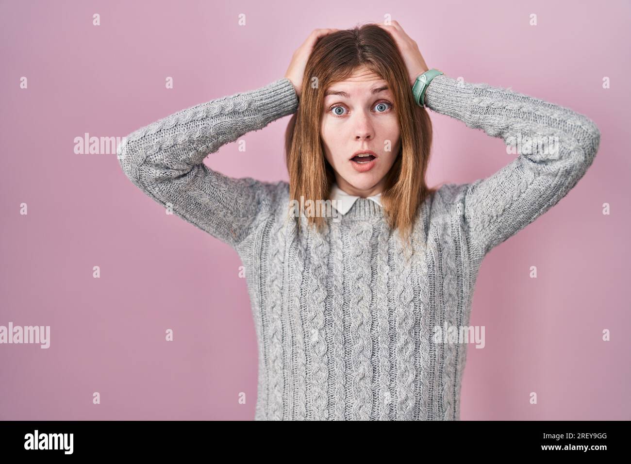 Beautiful woman standing over pink background crazy and scared with ...