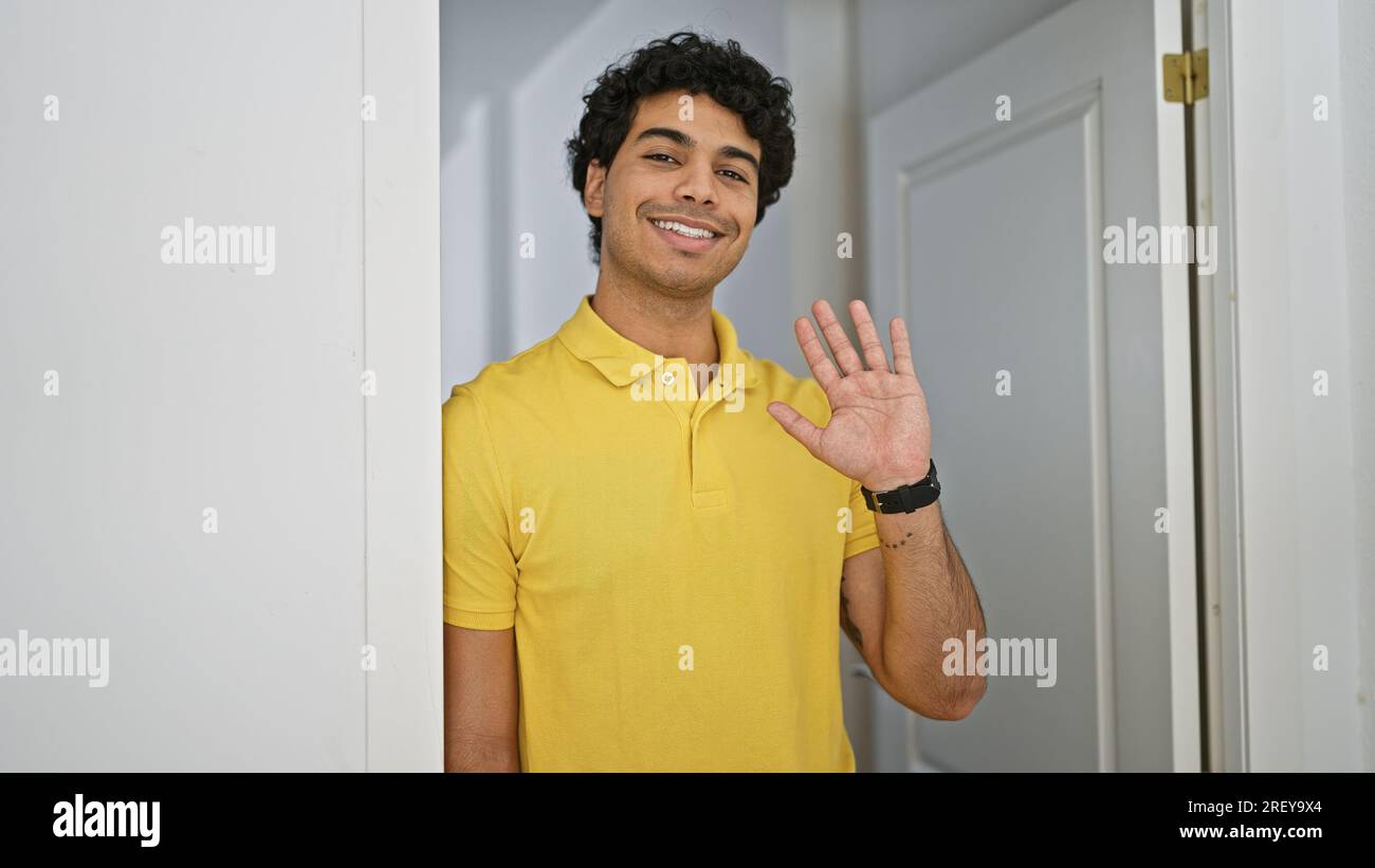 Young latin man smiling confident saying hello with hand at home Stock ...