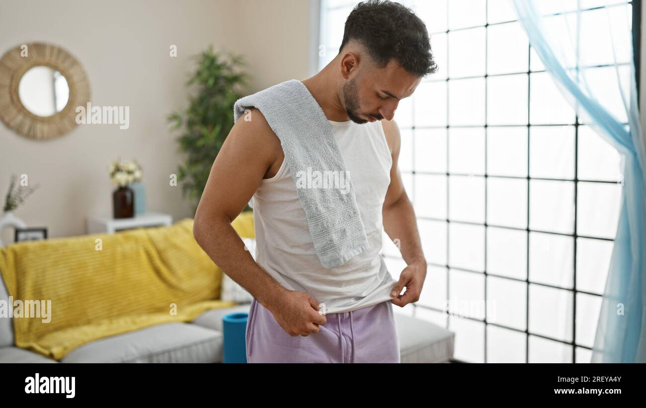 Young arab man standing tired using towel sweating at home Stock Photo ...