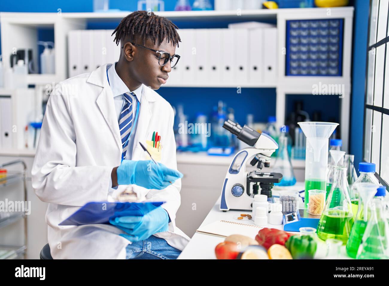 African american man scientist writing report at laboratory Stock Photo - Alamy