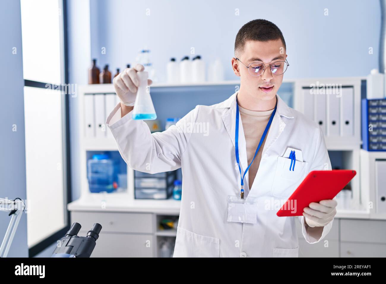 Young hispanic man scientist measuring liquid using touchpad at laboratory Stock Photo - Alamy