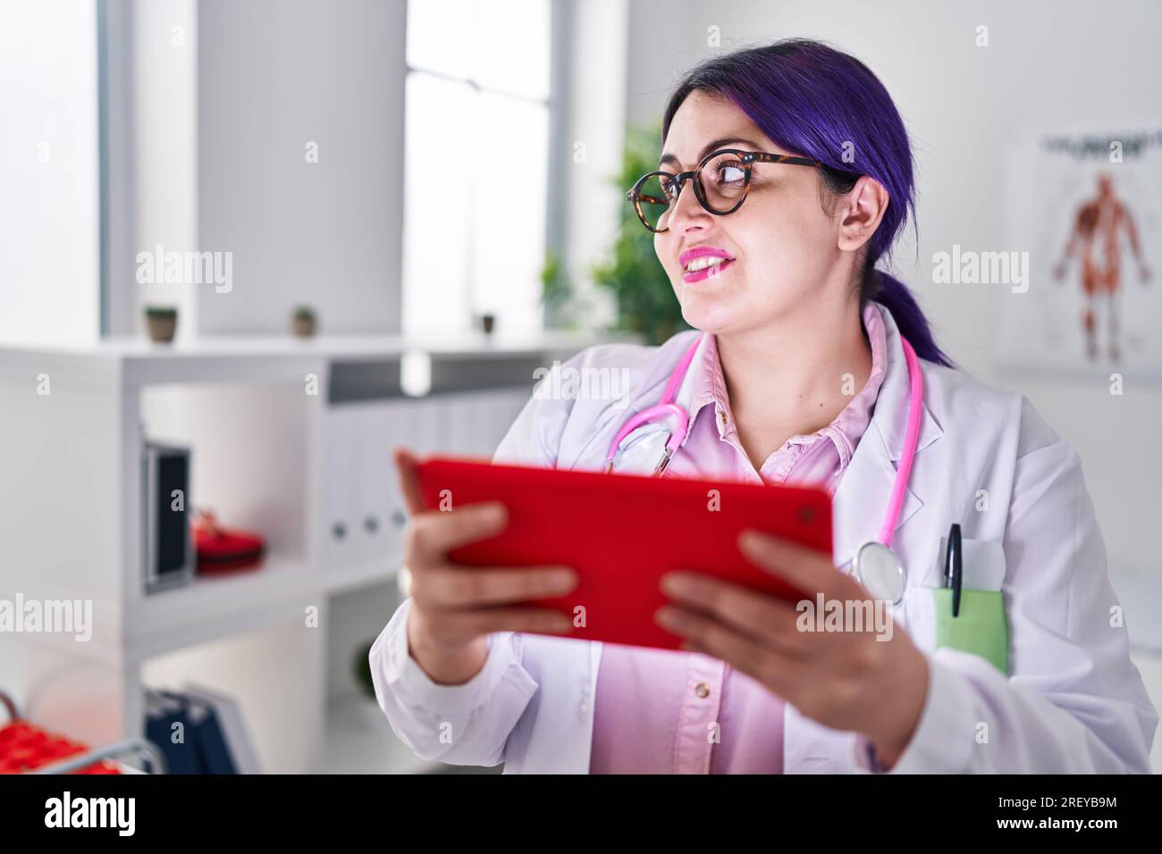 Young beautiful plus size woman doctor using touchpad standing at ...