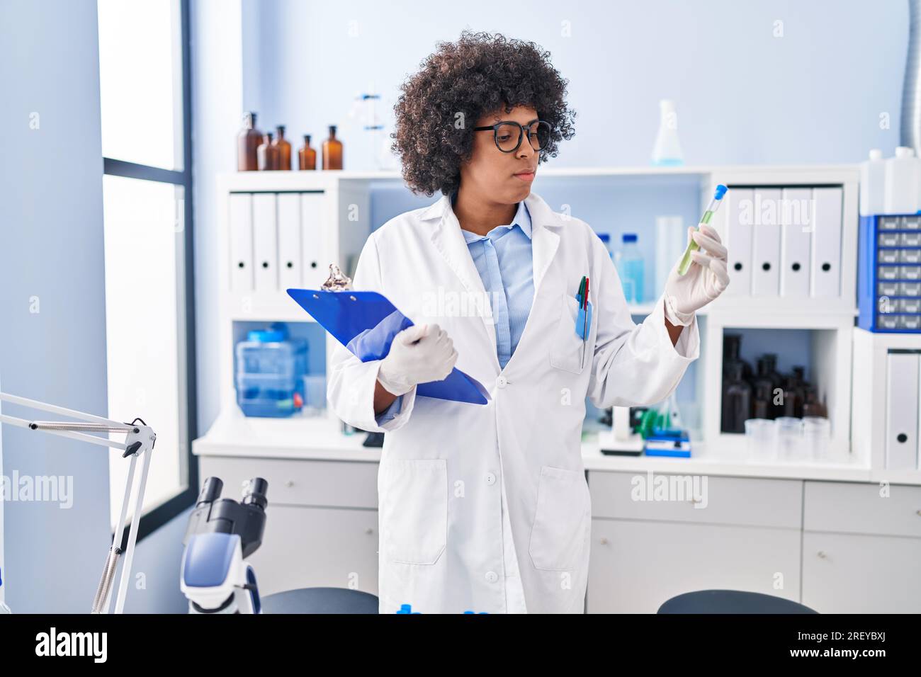 African american woman scientist reading report holding test tube at ...