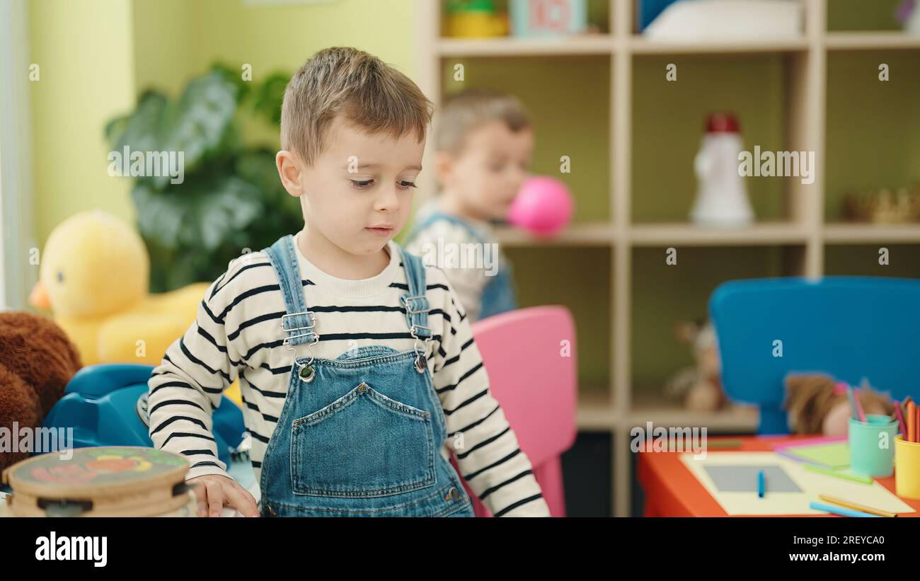 Adorable boys standing with relaxed expression playing at kindergarten ...