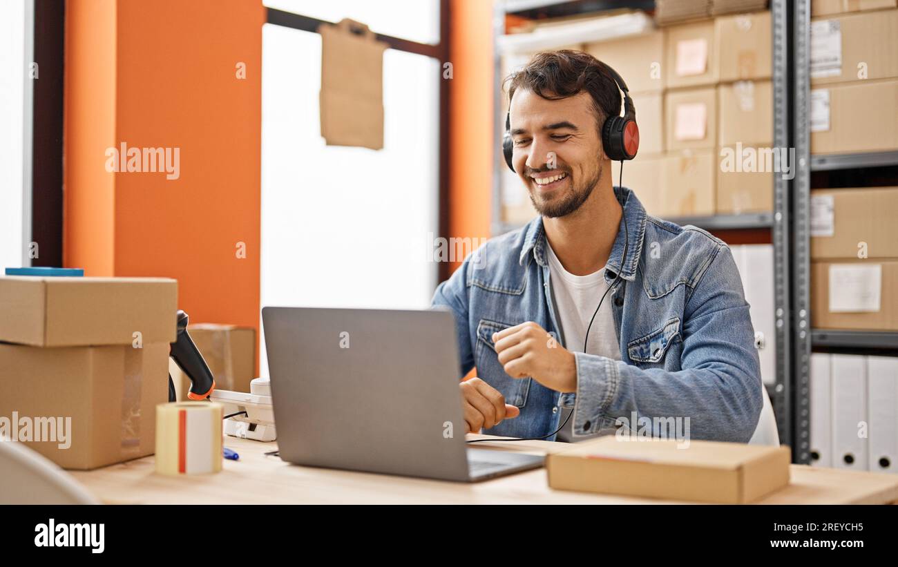 Young hispanic man ecommerce business worker listening to music dancing ...