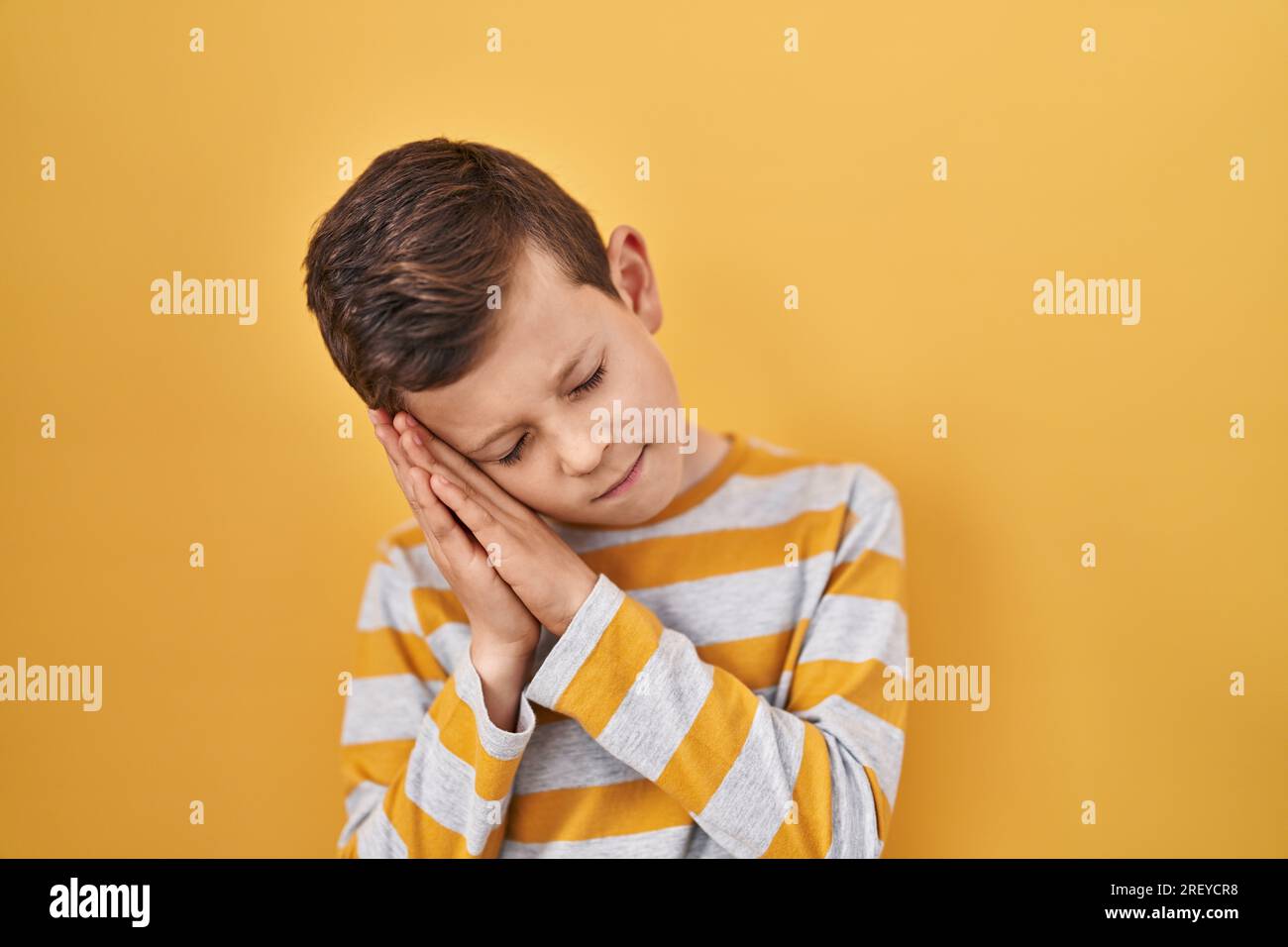 Young caucasian kid standing over yellow background sleeping tired ...