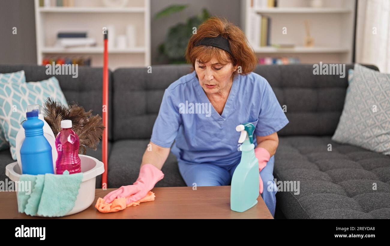 Middle age woman professional cleaner washing table home Stock Photo ...