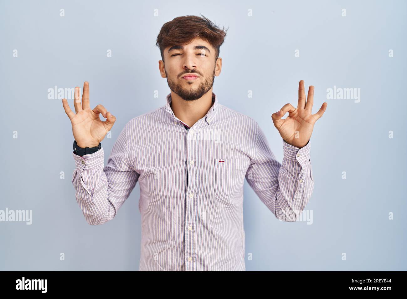 Arab man with beard standing over blue background relaxed and smiling ...