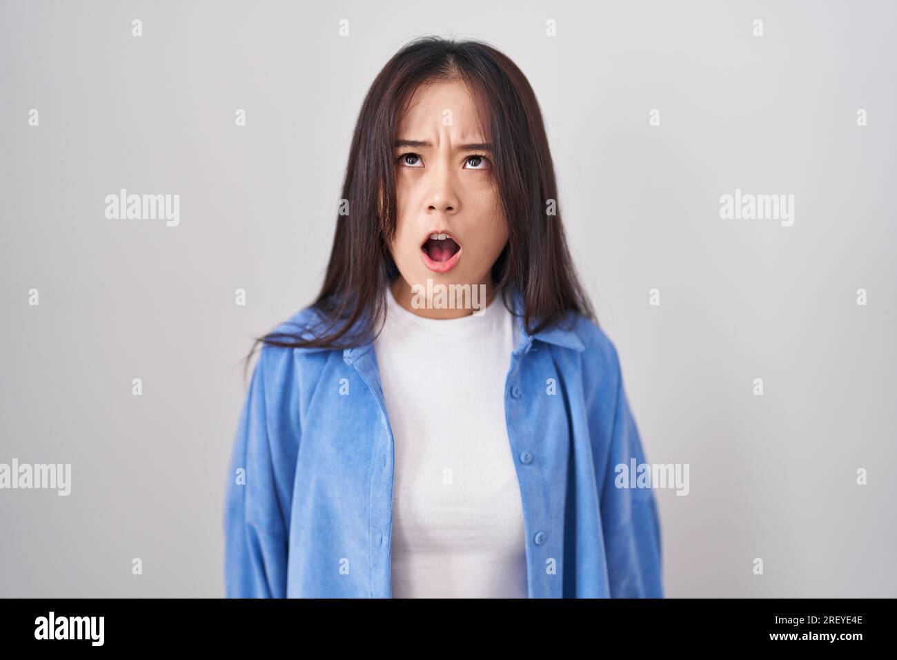 Young chinese woman standing over white background angry and mad ...