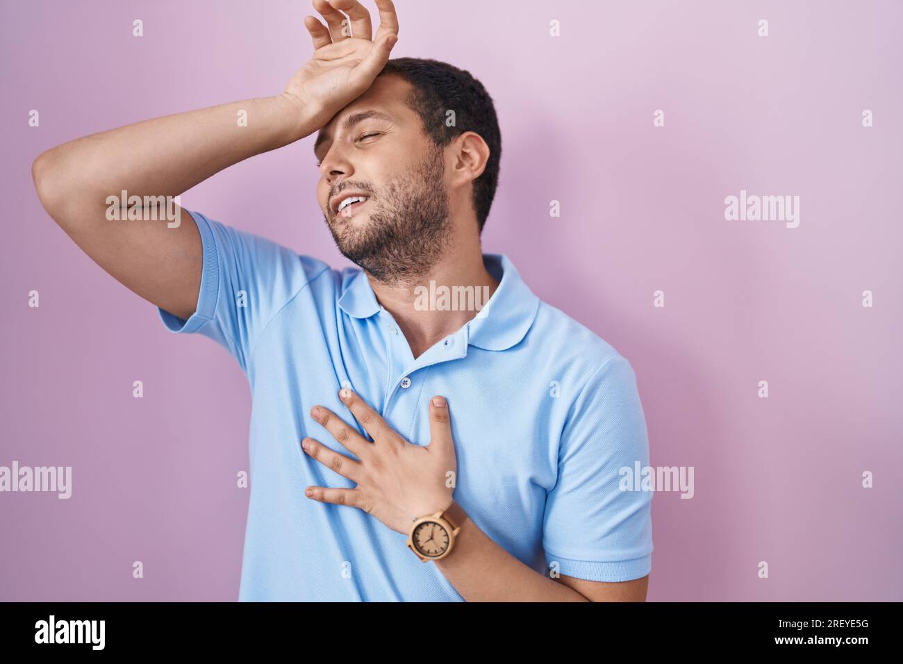 Hispanic man standing over pink background touching forehead for ...