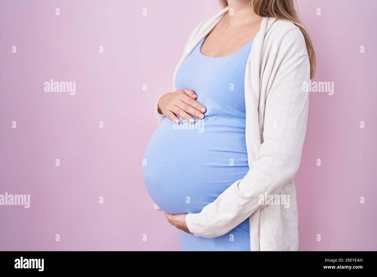Young pregnant woman expecting a baby, touching pregnant belly looking ...
