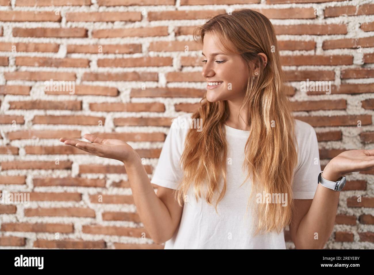 Young caucasian woman standing over bricks wall smiling showing both ...