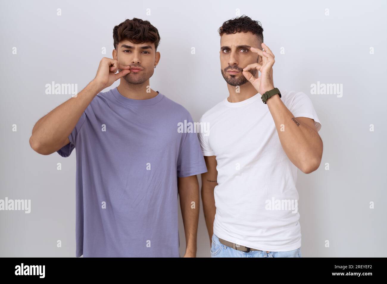 Homosexual gay couple standing over white background mouth and lips ...