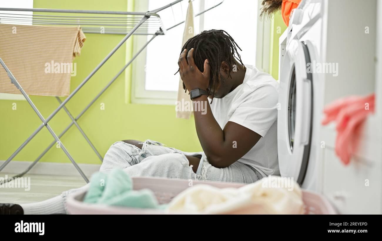 African american man waiting for washing machine stressed at laundry ...