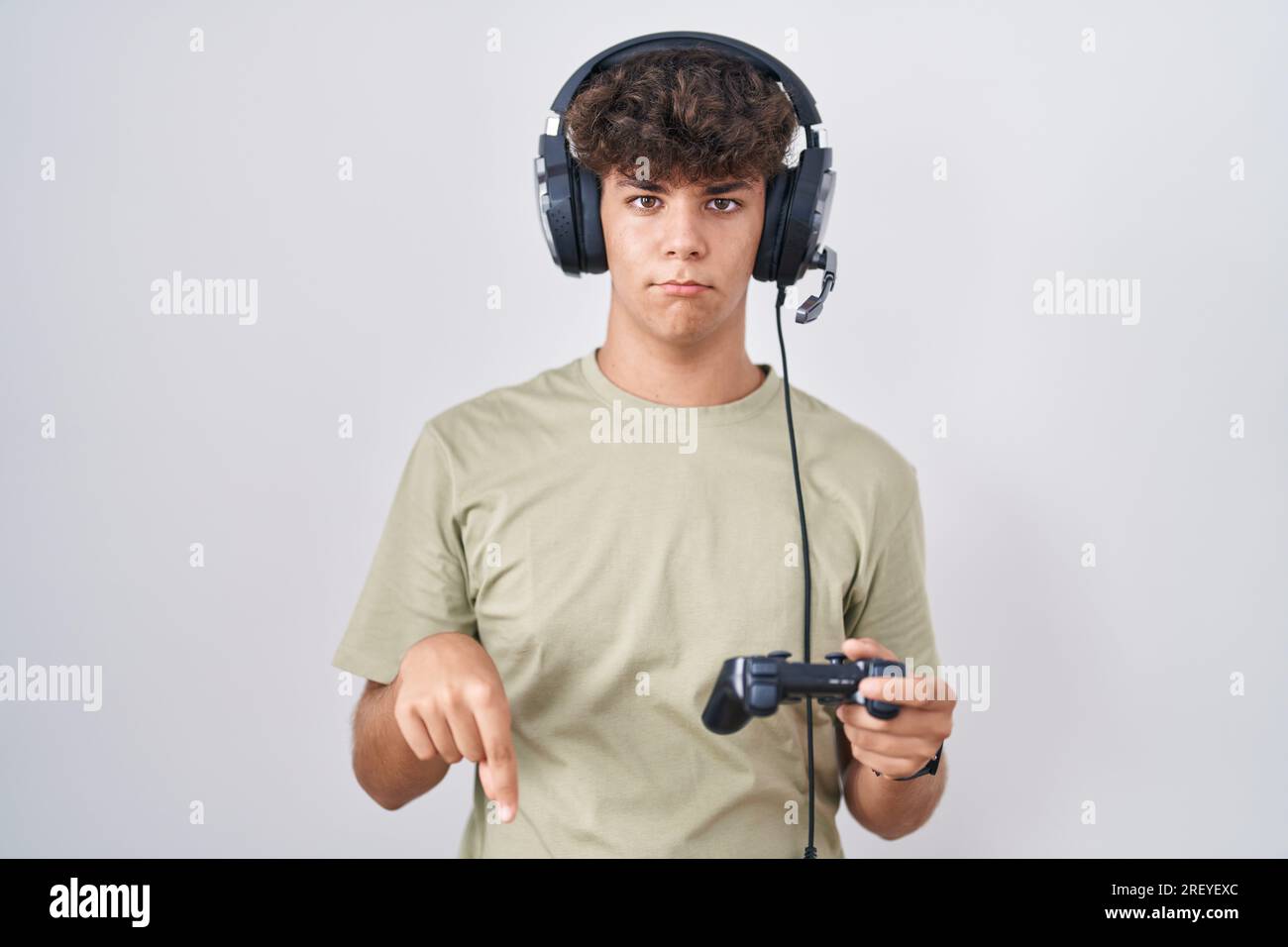 Hispanic teenager playing video game holding controller pointing down ...