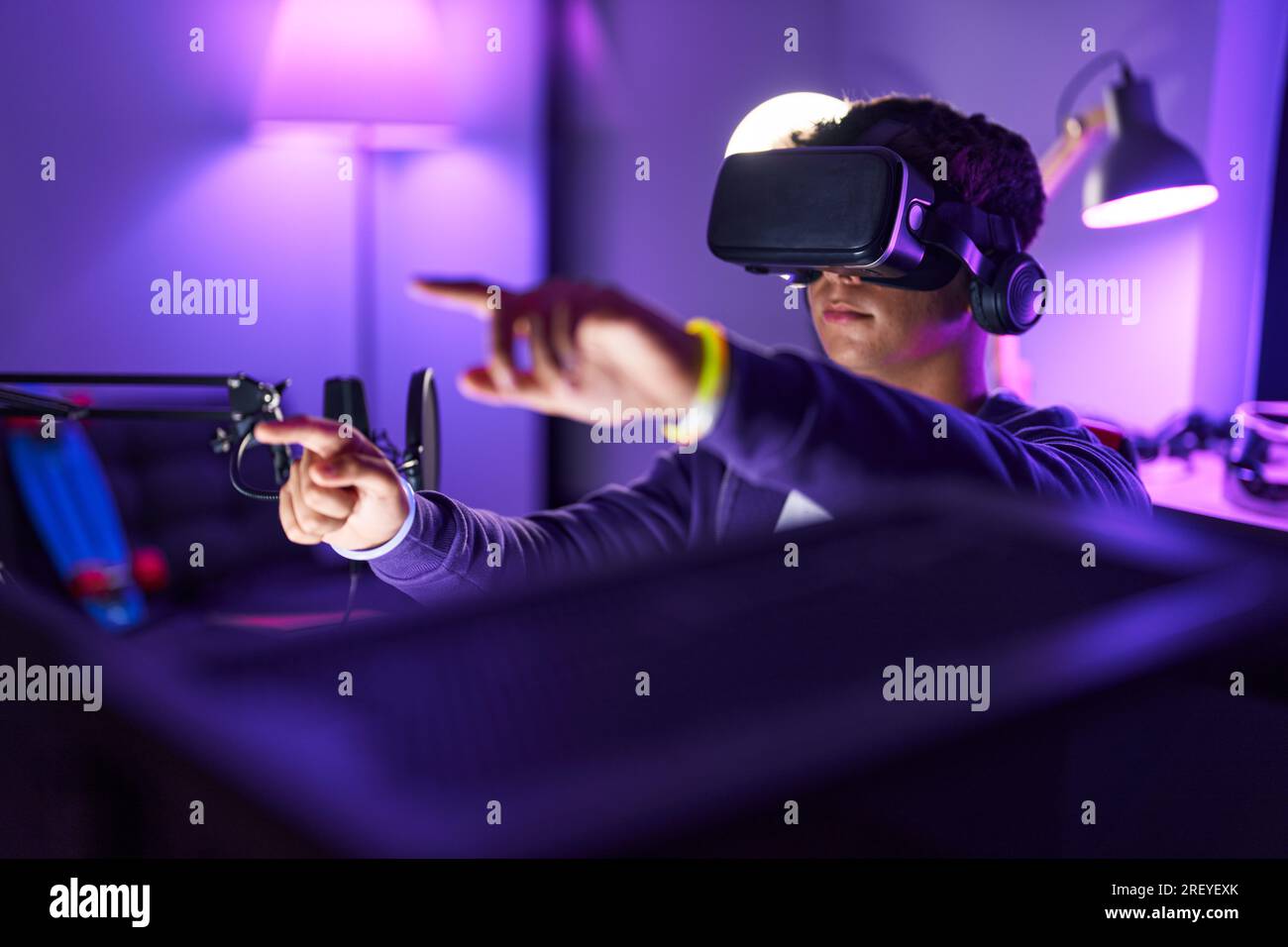 Young Hispanic Teenager Streamer Playing Video Game Using Virtual Reality Glasses At Gaming Room 