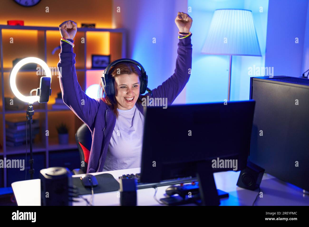 Young beautiful plus size woman streamer playing video game with winner ...