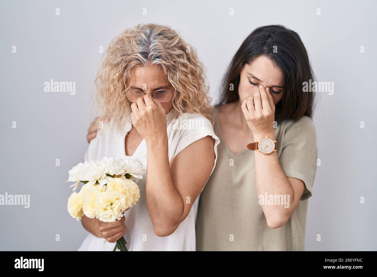 Mother and daughter holding bouquet of white flowers tired rubbing nose ...