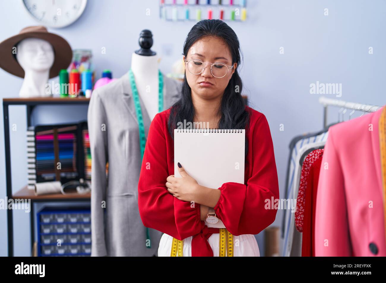 Asian young woman dressmaker standing by manikin depressed and worry ...