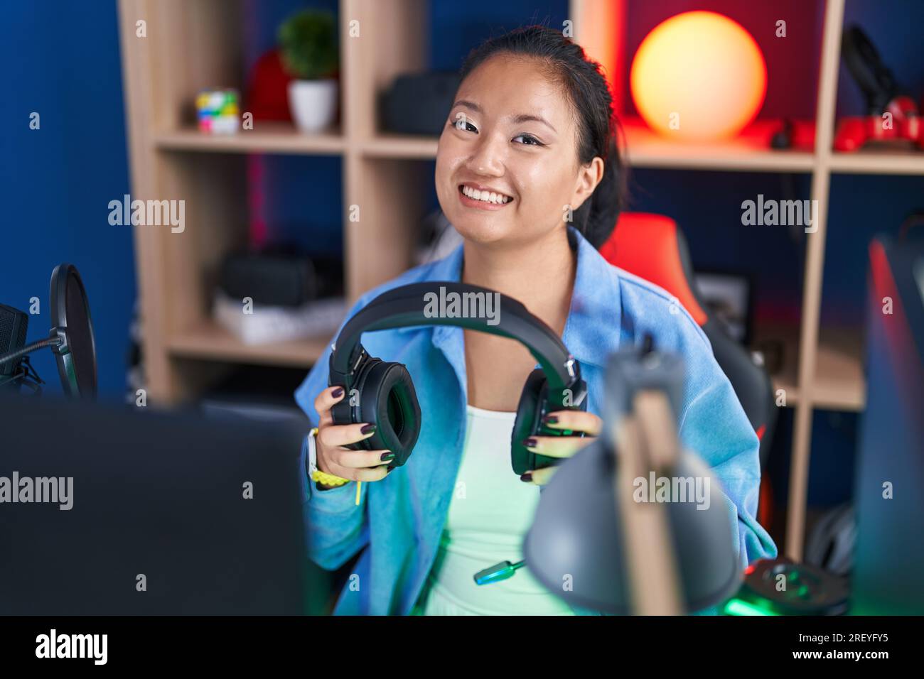 Young chinese woman streamer smiling confident holding headphones at ...