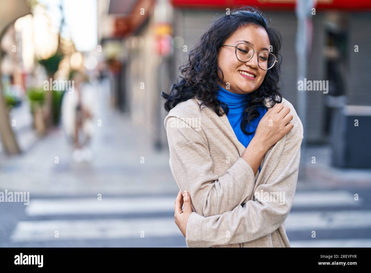 Young chinese woman smiling confident hugging himself at street Stock ...