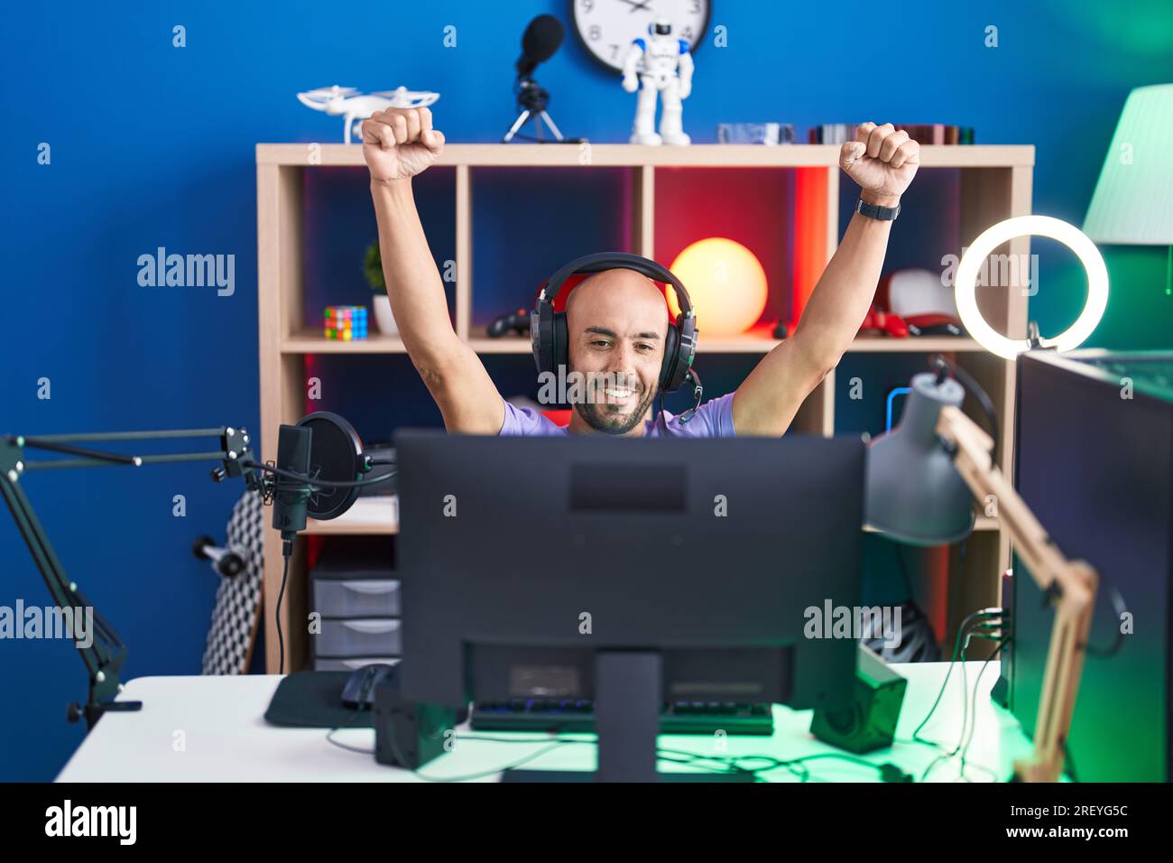 Young bald man streamer playing video game with winner expression at ...