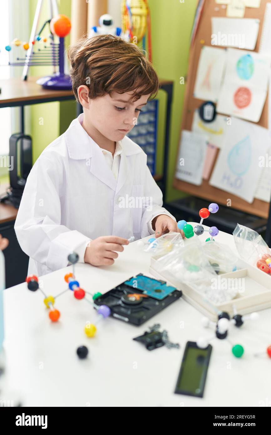 Adorable caucasian boy student looking molecules at laboratory ...
