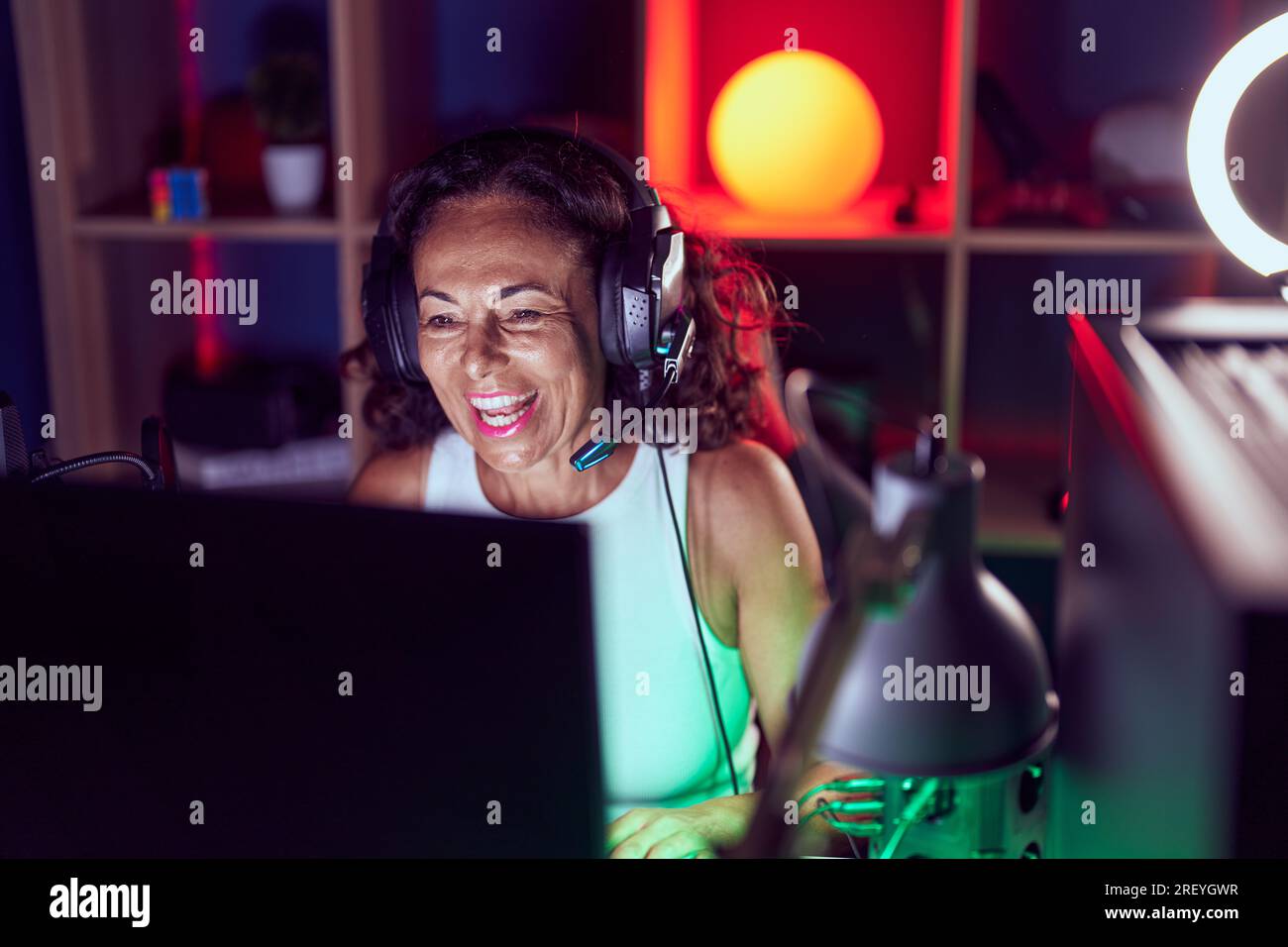 Middle age woman streamer playing video game using computer at gaming ...