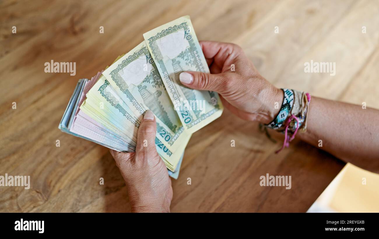 Middle age hispanic woman counting bangladesh taka banknotes at home ...