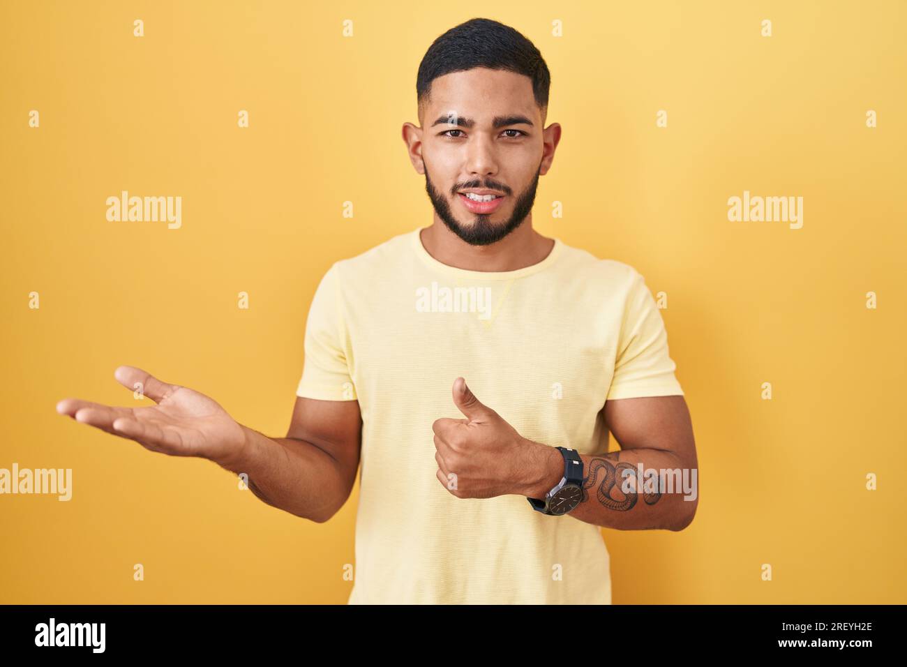 Young hispanic man standing over yellow background showing palm hand ...