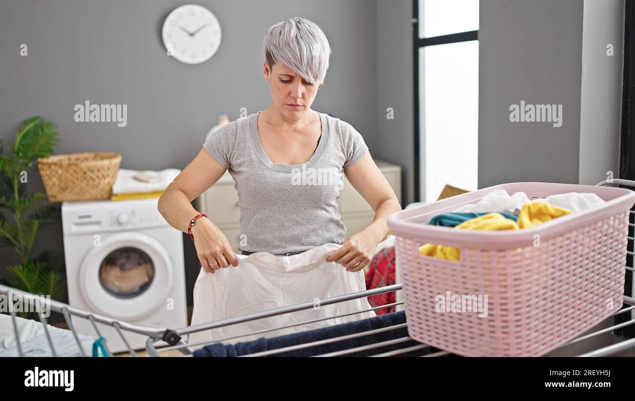 Young woman hanging clothes on clothesline at laundry room Stock Photo ...