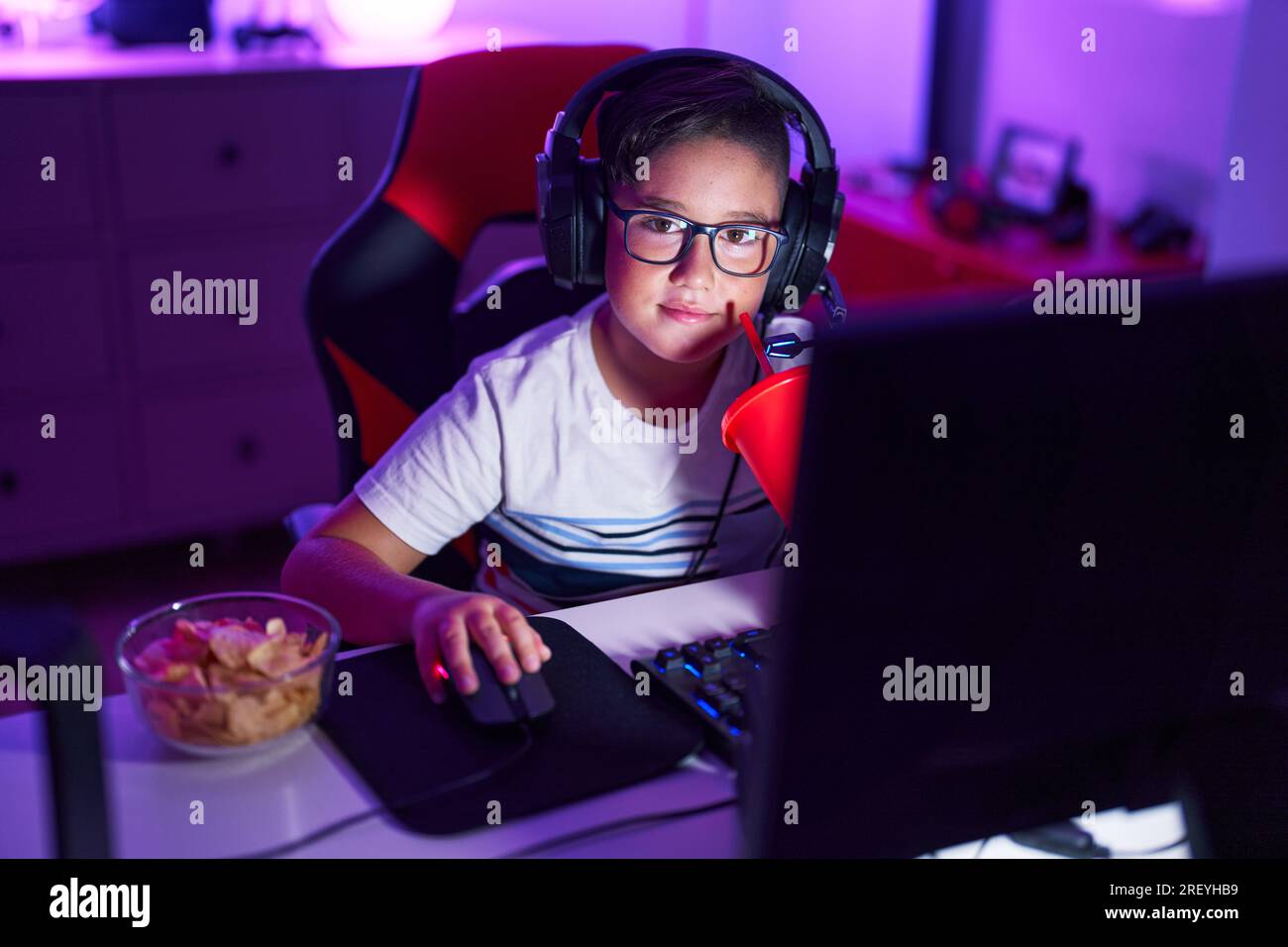 Adorable hispanic boy streamer playing video game drinking beverage at ...