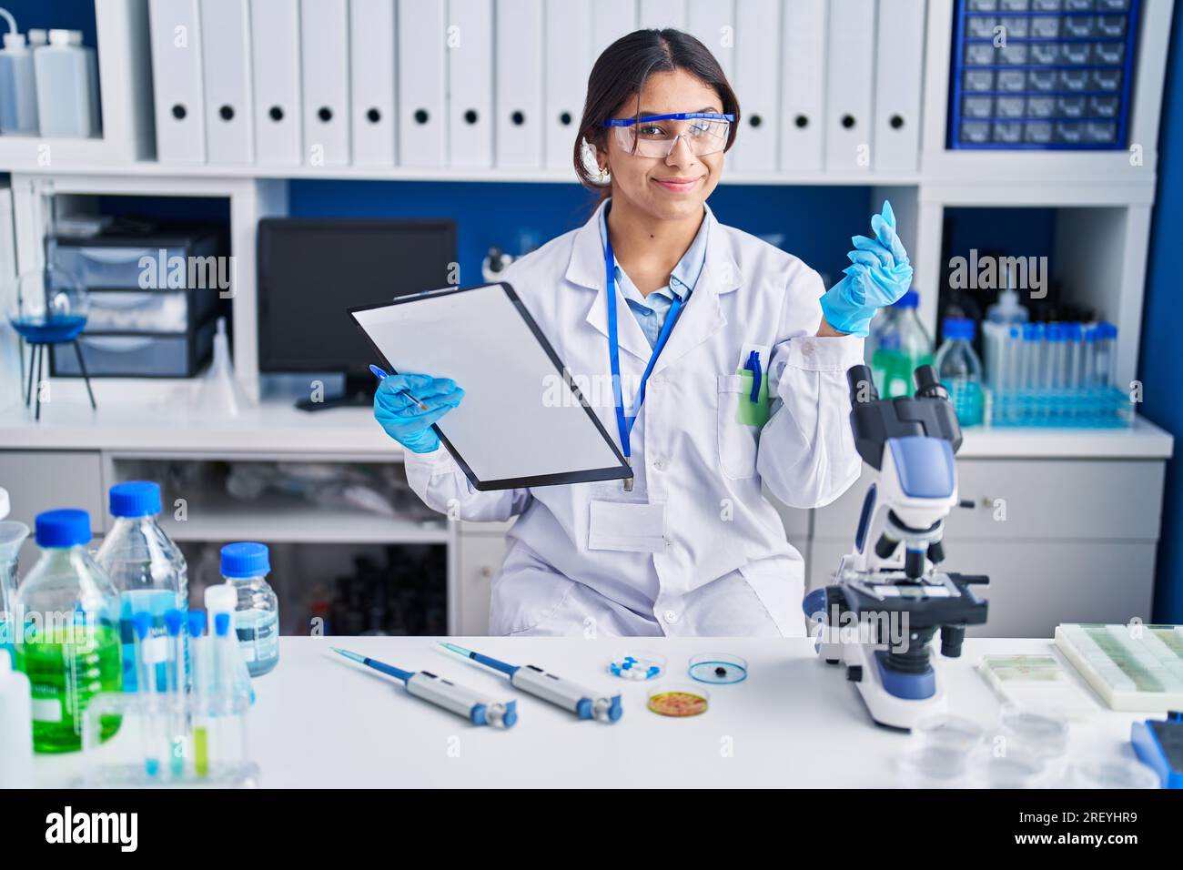 Hispanic young woman working at scientist laboratory doing money ...
