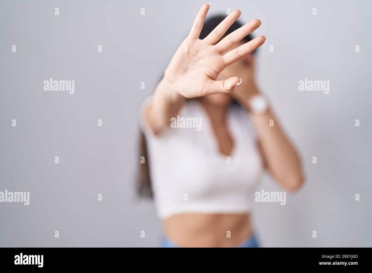Young teenager girl standing over white background covering eyes with ...