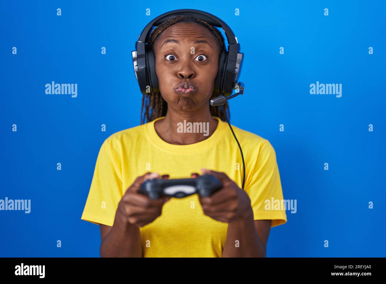 African american woman playing video games puffing cheeks with funny ...