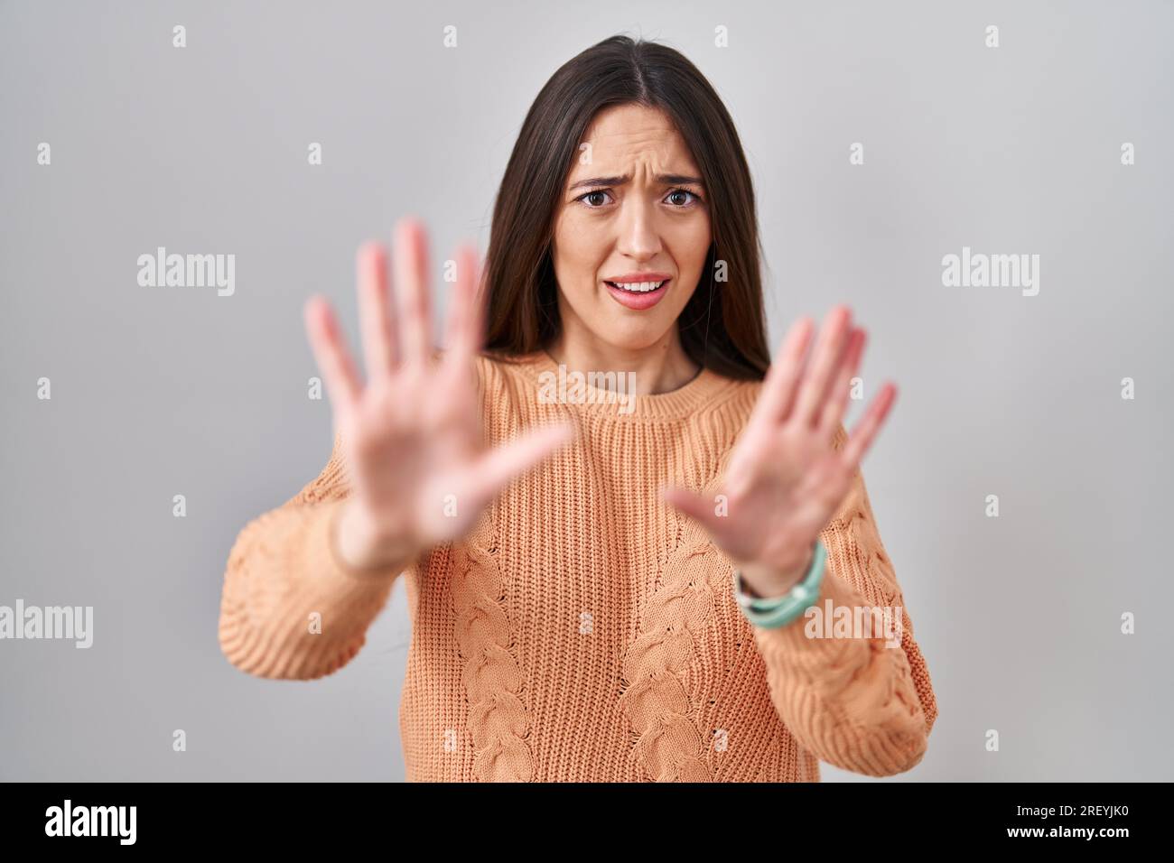 Young brunette woman standing over white background afraid and ...