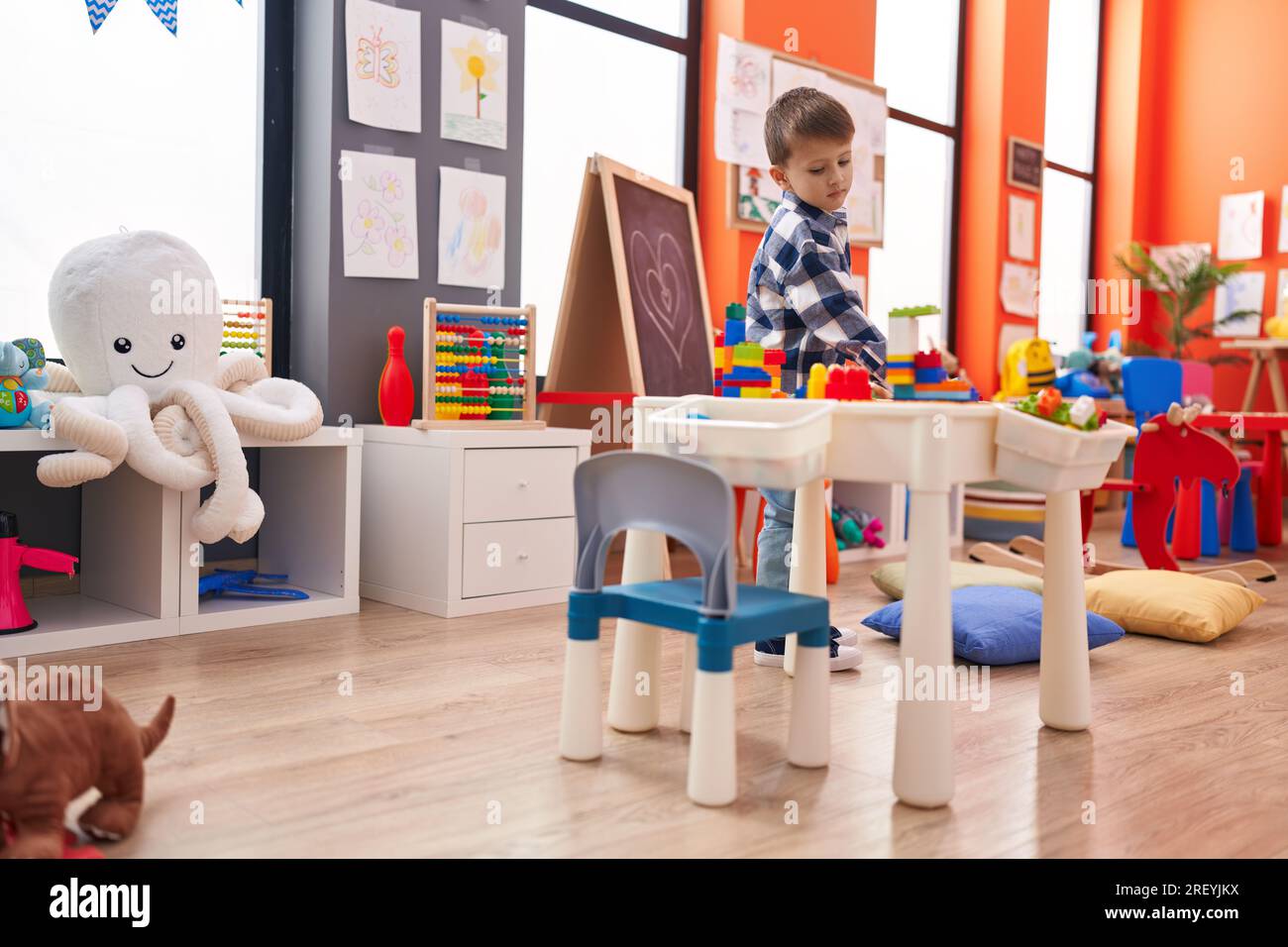 Adorable caucasian boy playing with construction blocks standing at ...