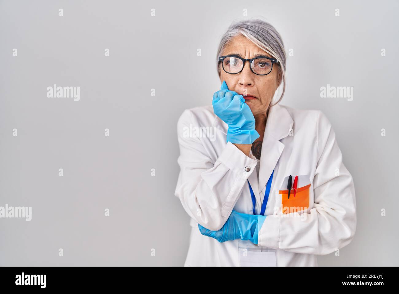 Middle age woman with grey hair wearing scientist robe looking stressed ...