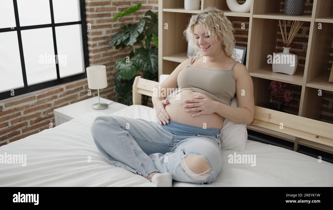 Young Pregnant Woman Touching Belly Sitting On Bed At Bedroom Stock 4646