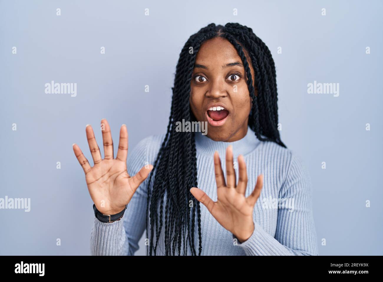 African american woman standing over blue background afraid and ...