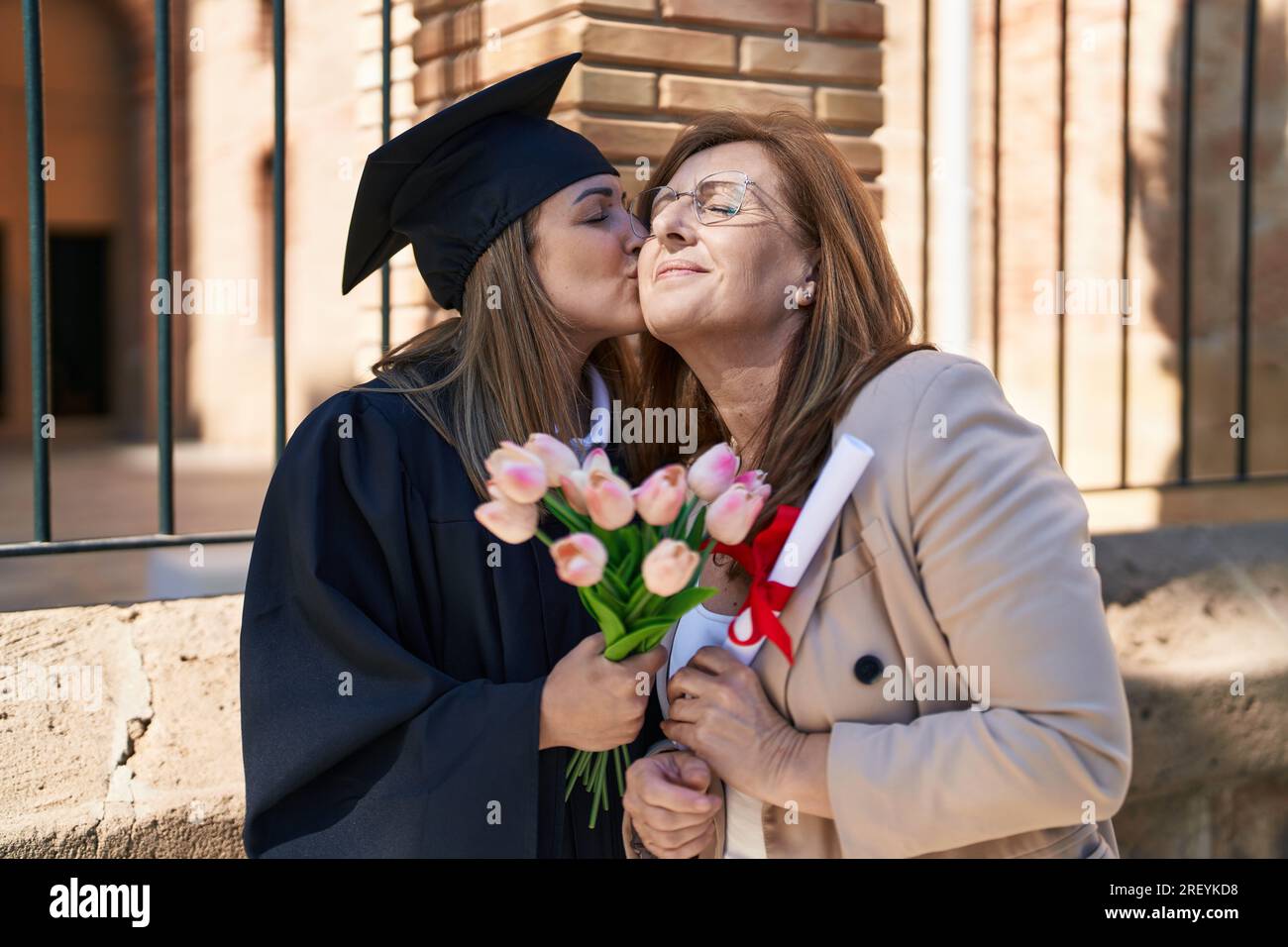 Mother and daughter hugging each other celebrating graduation holding ...